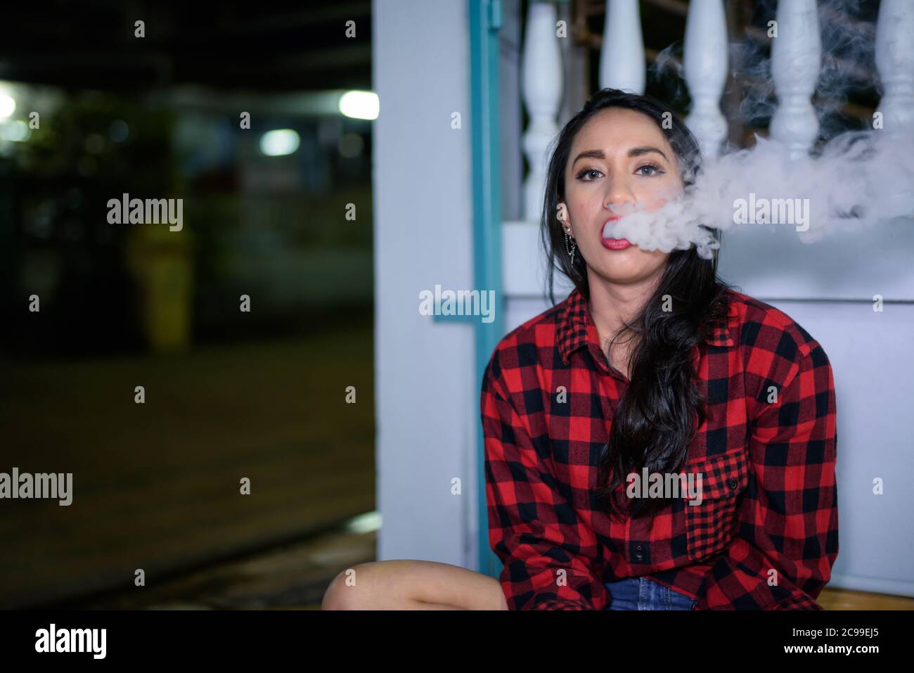 Young beautiful Asian woman vaping at home outdoors Stock Photo - Alamy