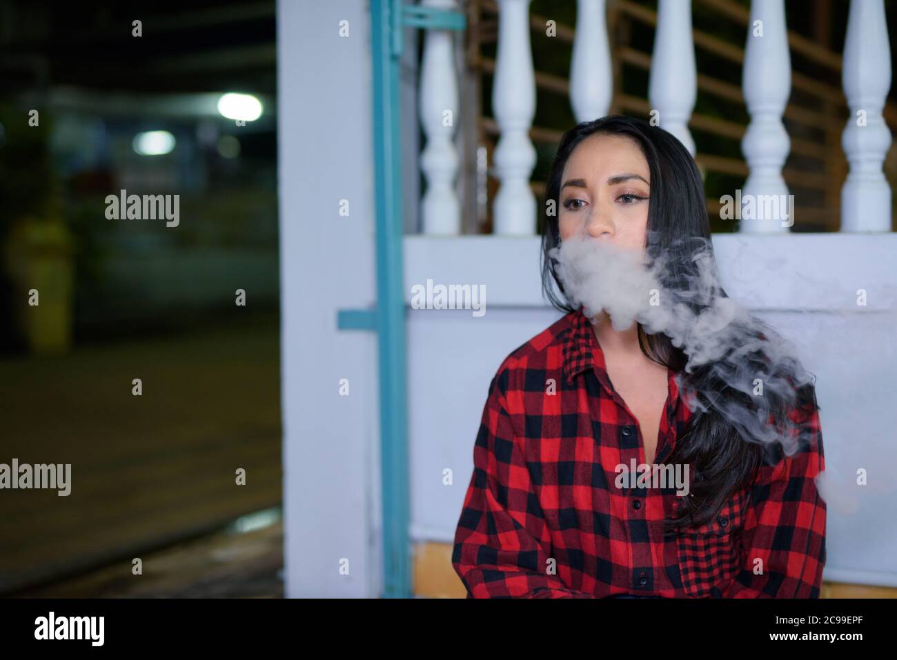 Young beautiful Asian woman vaping at home outdoors Stock Photo - Alamy