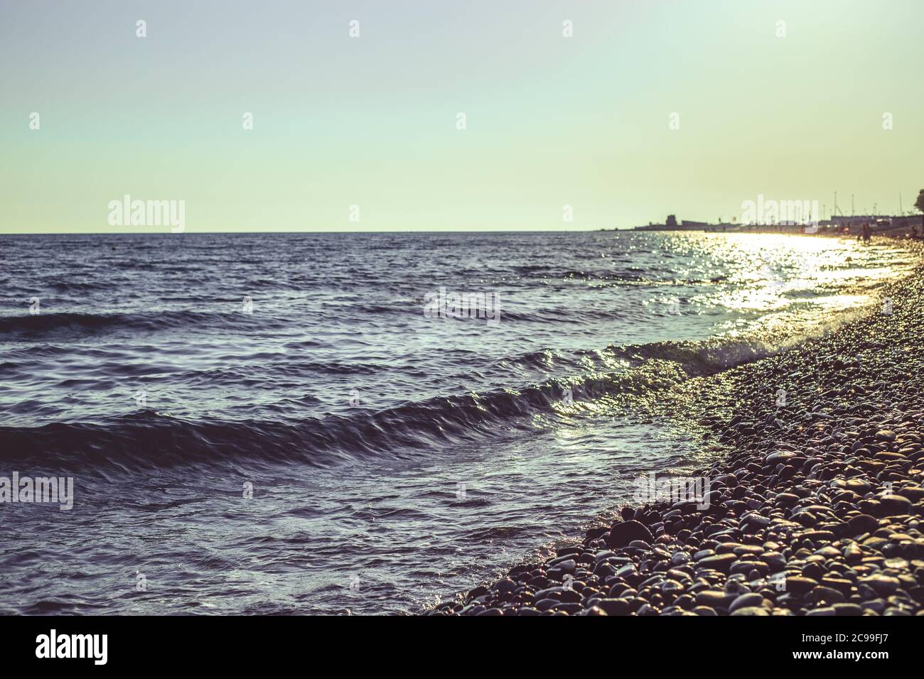 Pebbles on the beach in the sunset light. Blurred background in the ...