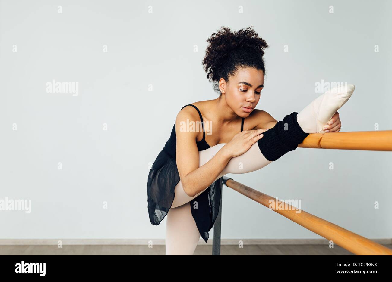 Female ballet dancer stretching her leg. Young woman preparing for a ...