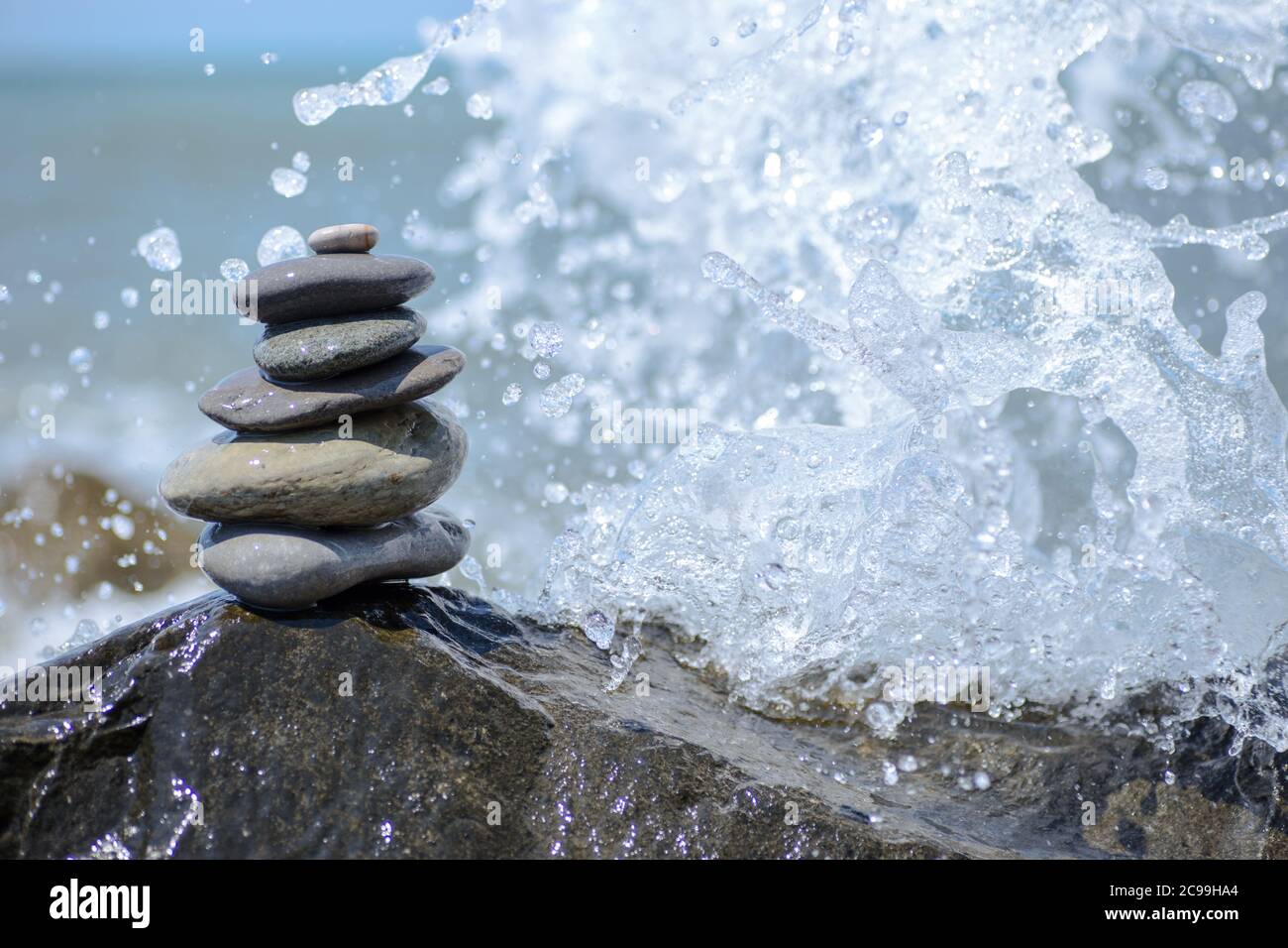 Balance zen stones pyramid on pebble beach with a splashing wave ...