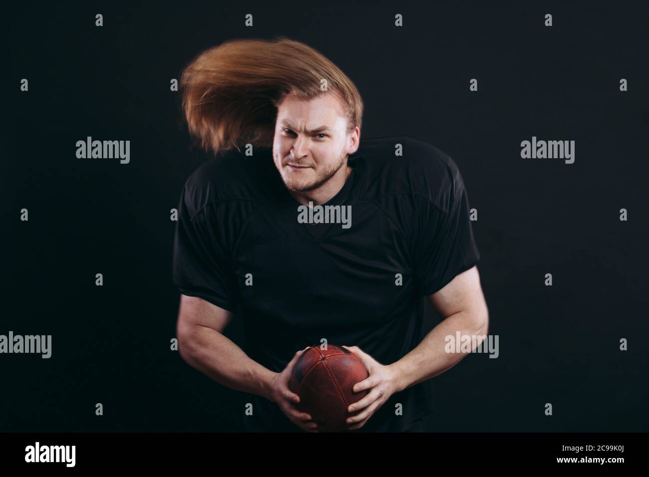Healthy american football goalkeeper holding ball in arms looking at ...