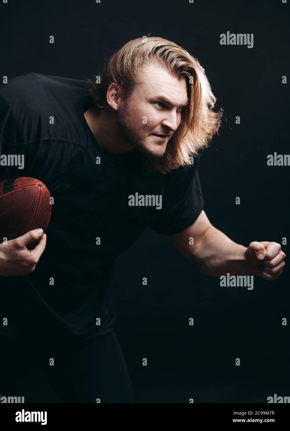 Portrait of determined American football player in black uniform with ...