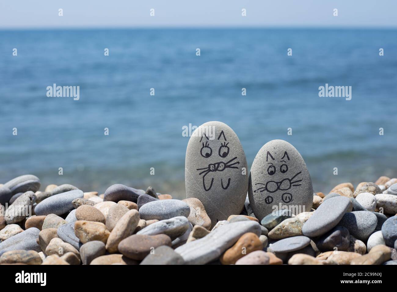 Pebbles with drawn faces in the sand. Loving couple. Travel concept ...