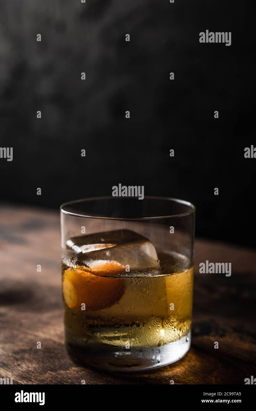 Old fashioned cocktail in a rocks glass with a big ice cube, back light ...