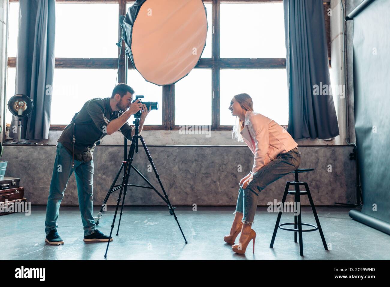 stylish girl bending to the photographer in the room, side view photo ...