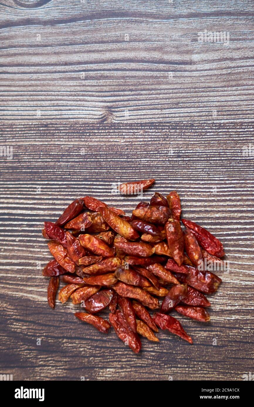 Vertical high angle shot of a pile of red chili peppers on a wooden ...