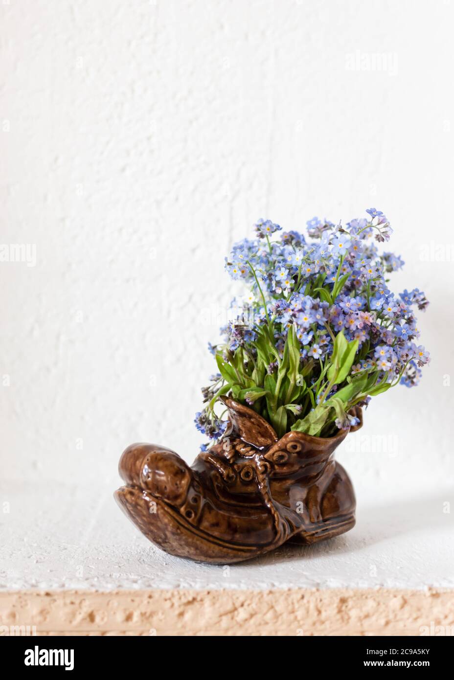 Ceramic slipper with a bouquet of forget-me-nots on a white background ...