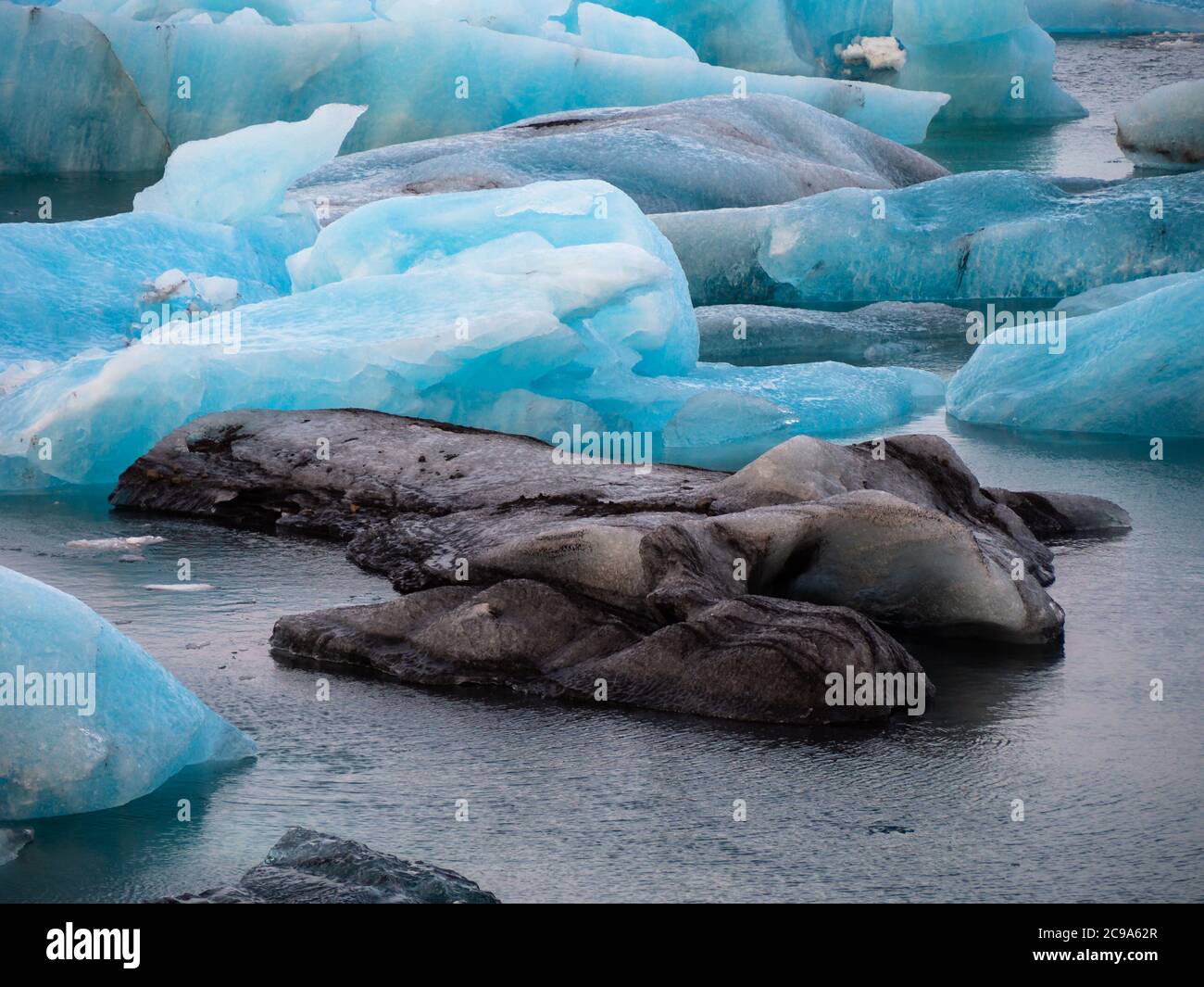 A black Iceberg in a lagoon of blue Icebergs Stock Photo - Alamy