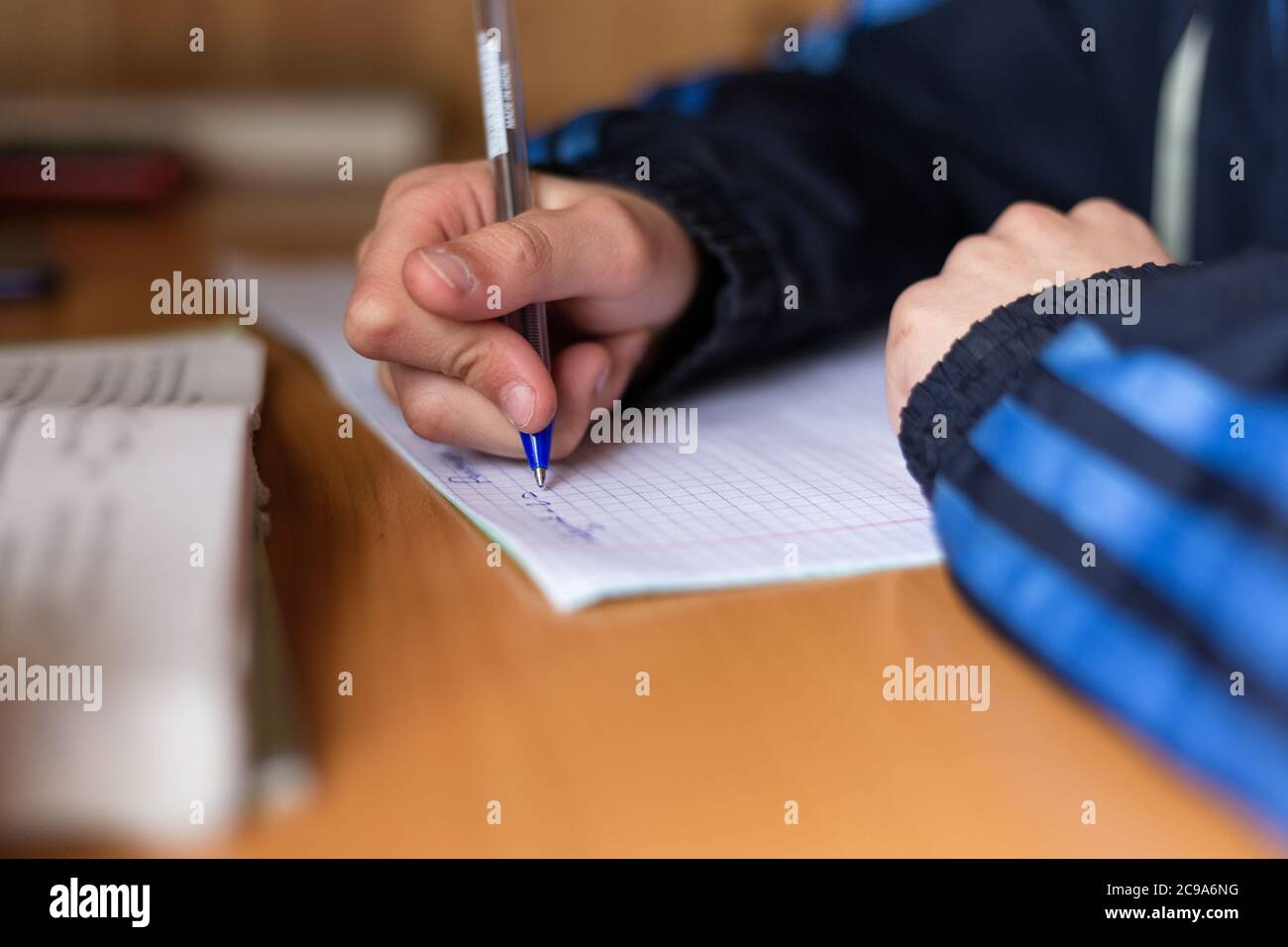 The boy writes in a notebook. The child is doing homework. Pen and ...