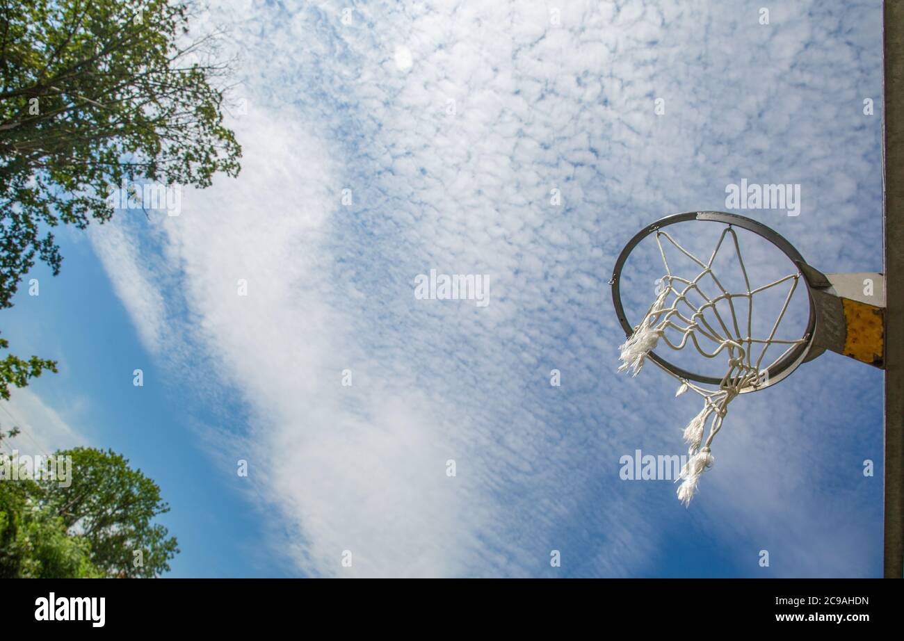 A broken basketball net dangles from a hoop attached to a metal ...