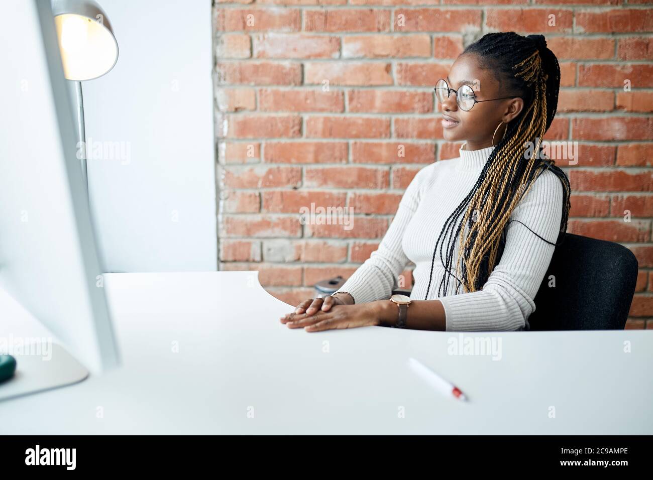 serious Afro secretary looking at the screen of the computer at ...