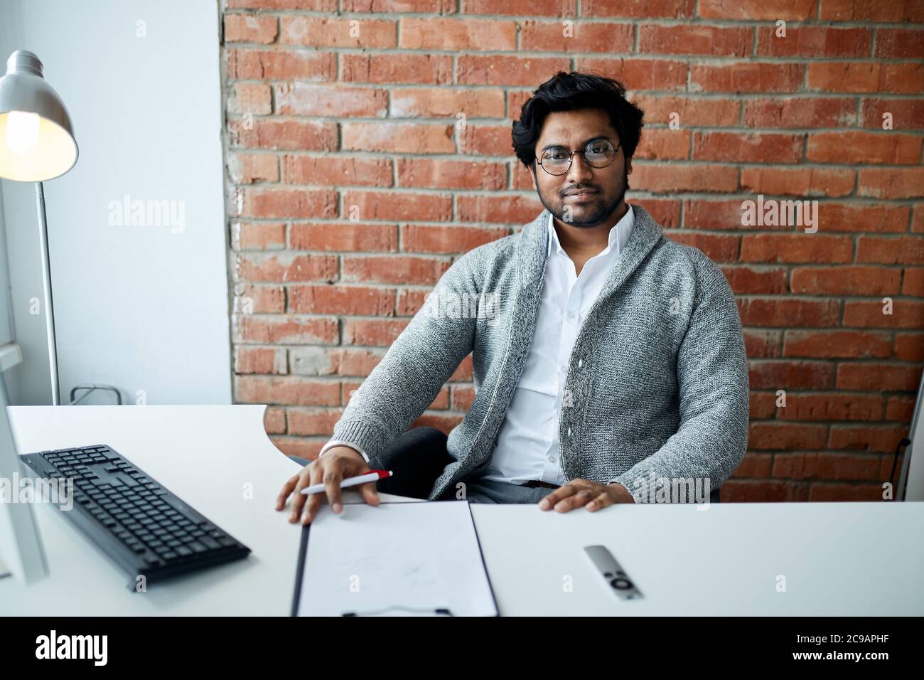 positive handsome Indian man sitting in front of the computer and ...