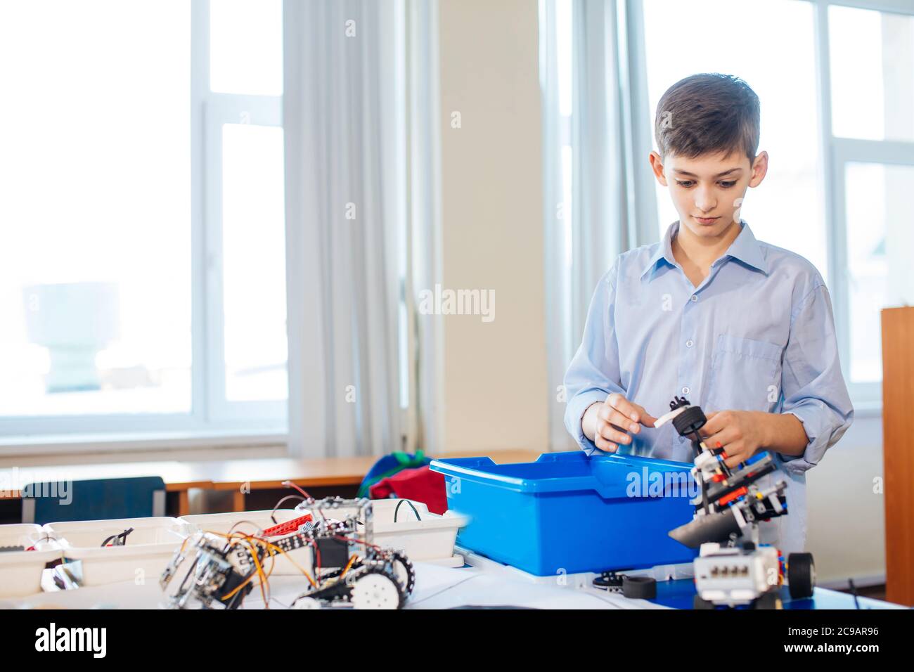Curious handsome young technician in white shirt creating robot in well ...