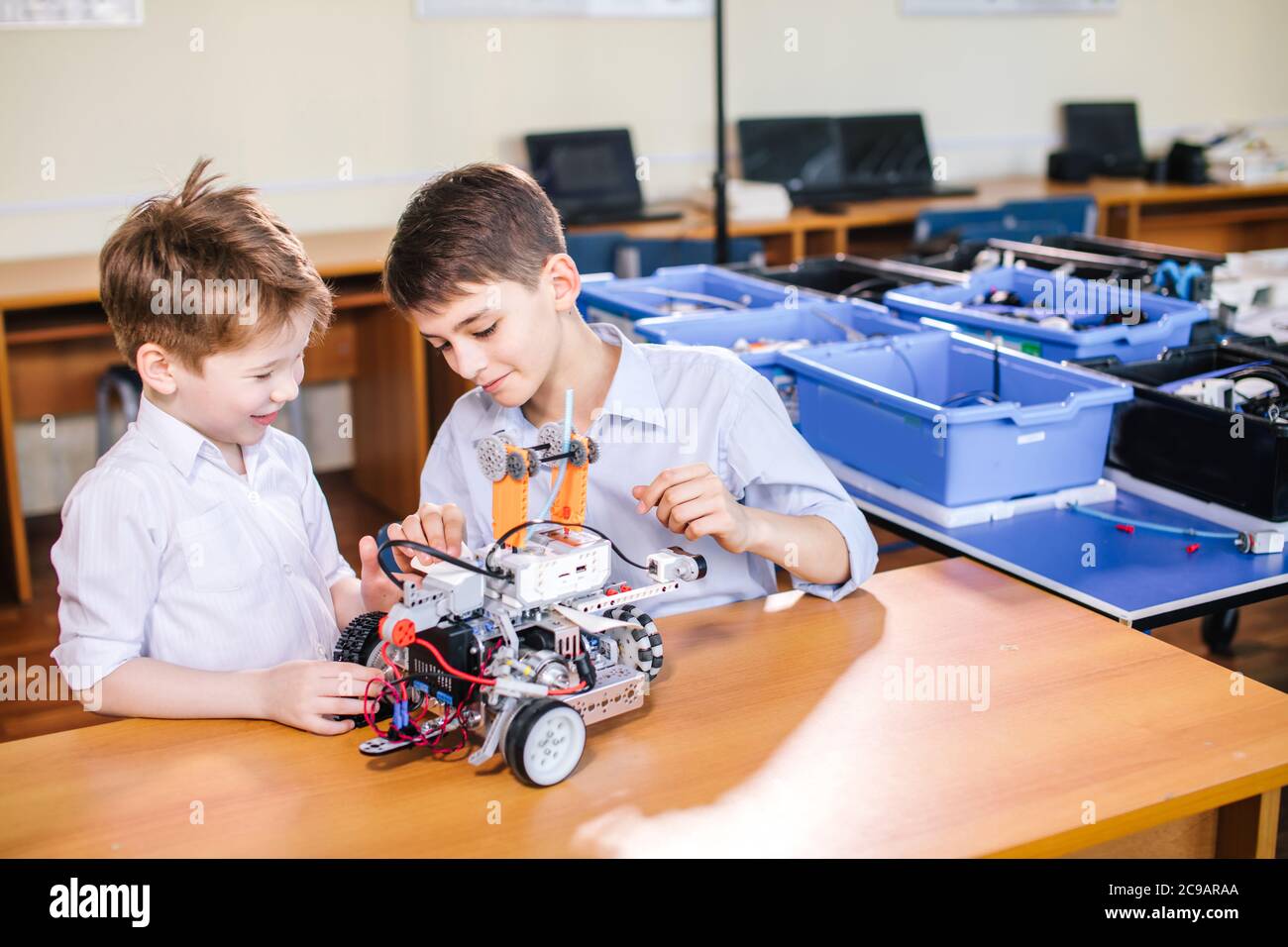 Two brothers kids of different age playing with robot toy at school ...