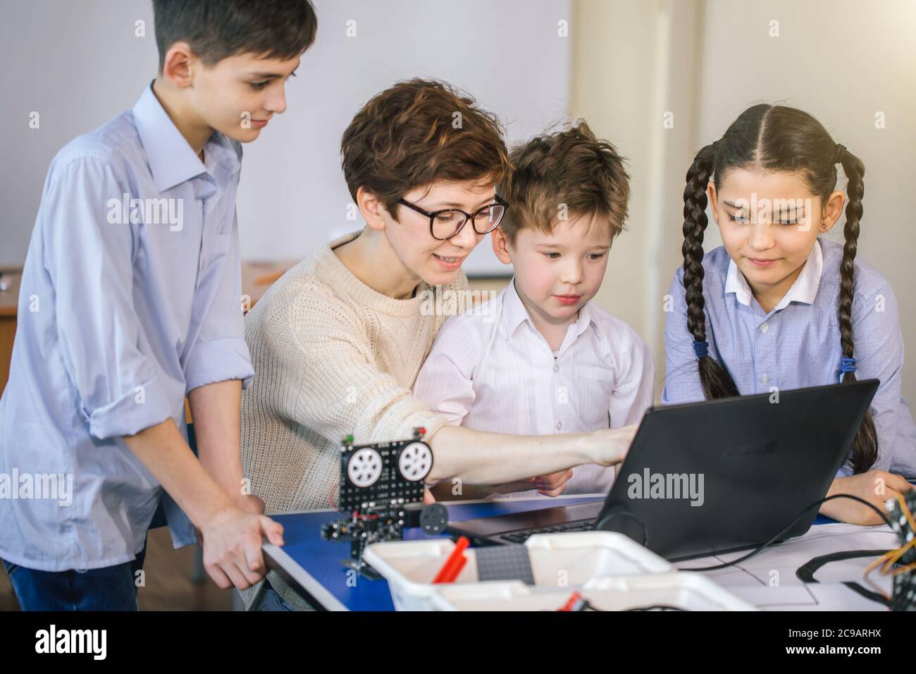 group of happy kids with their female adult science prof with tablet pc ...