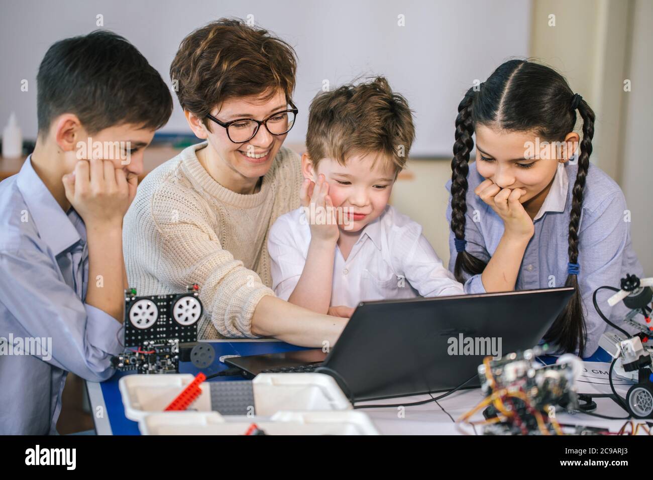 Smart kids with their mother learn programming using laptop at home ...
