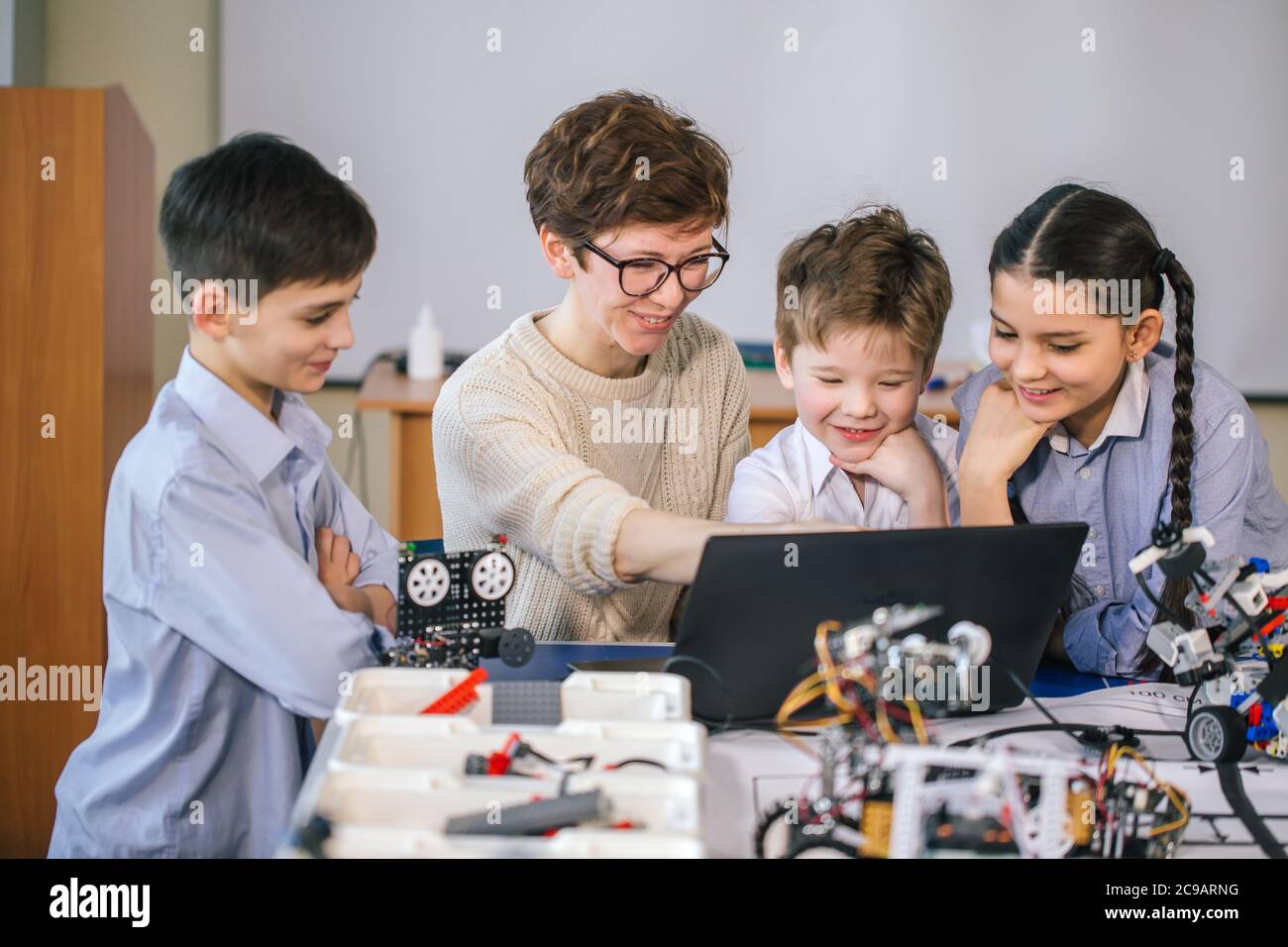 group of happy kids with their female adult science prof with tablet pc ...