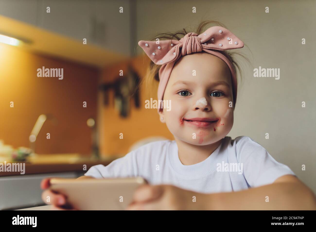 Girl eating at the table playing on the phone Stock Photo - Alamy