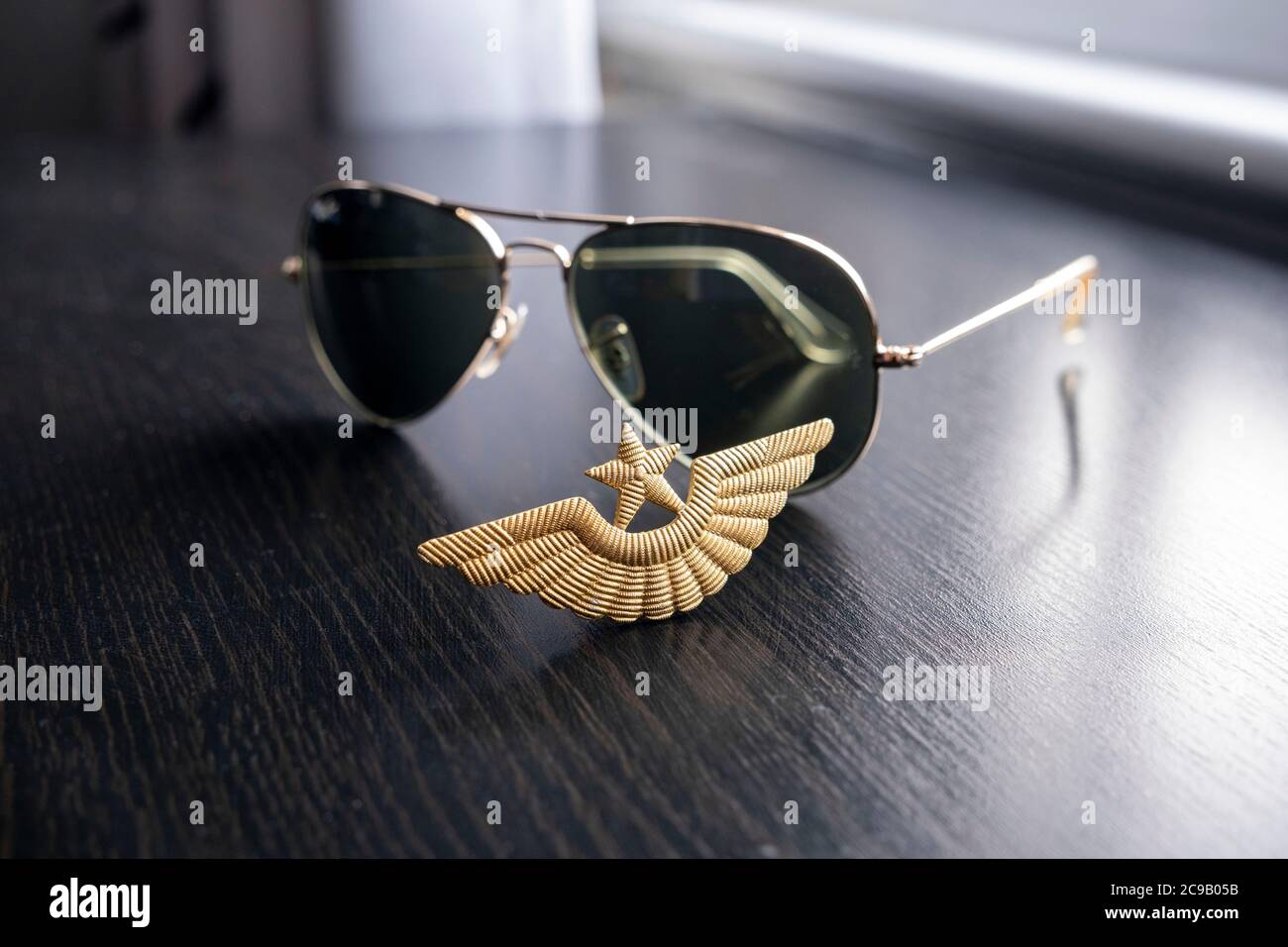 Gold coloured pilot's wings cap badge and aviator style sun glasses ...