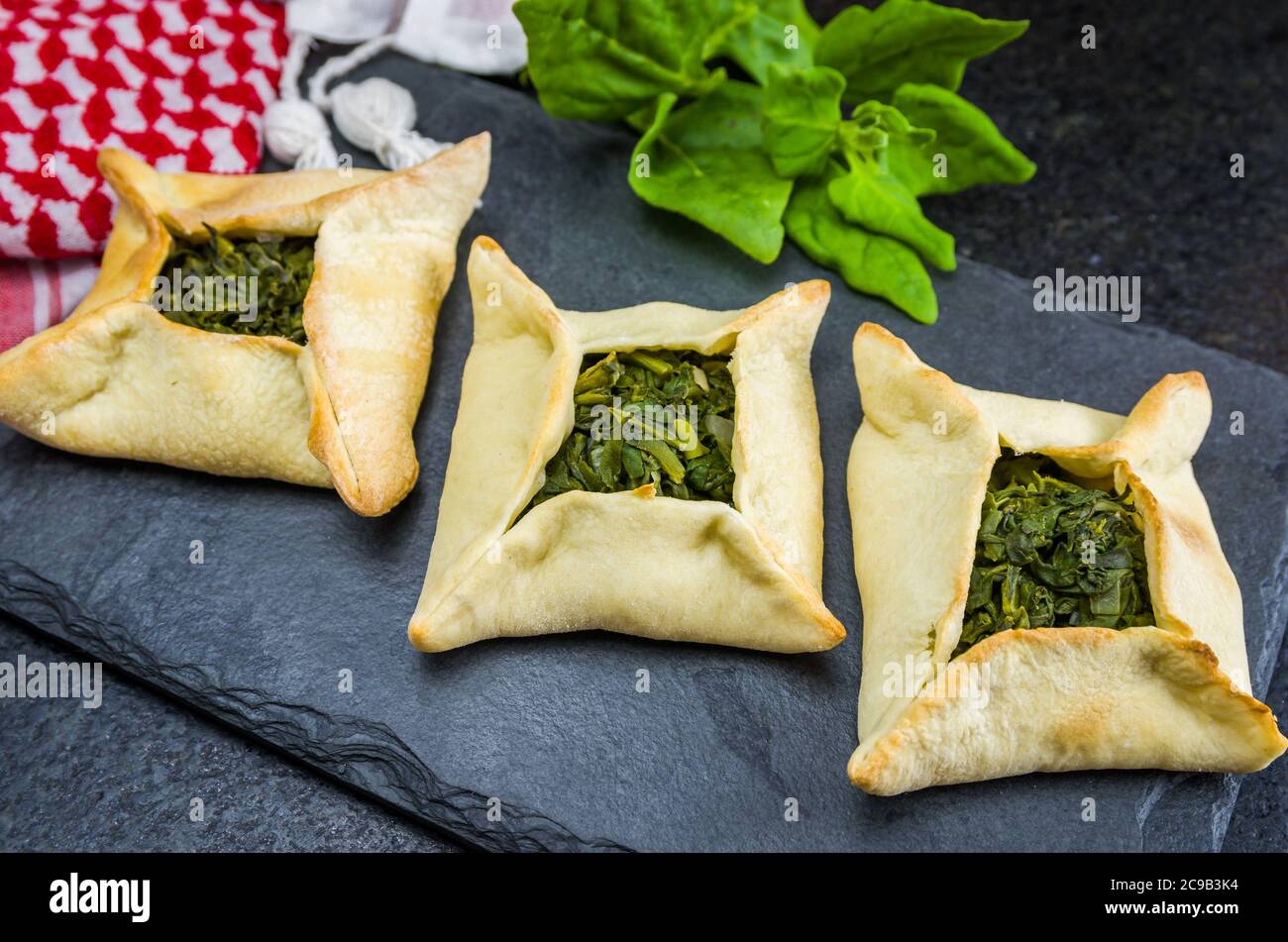 Delicious Lebanese (Arabic) food, spinach sfiha on black slate stone ...