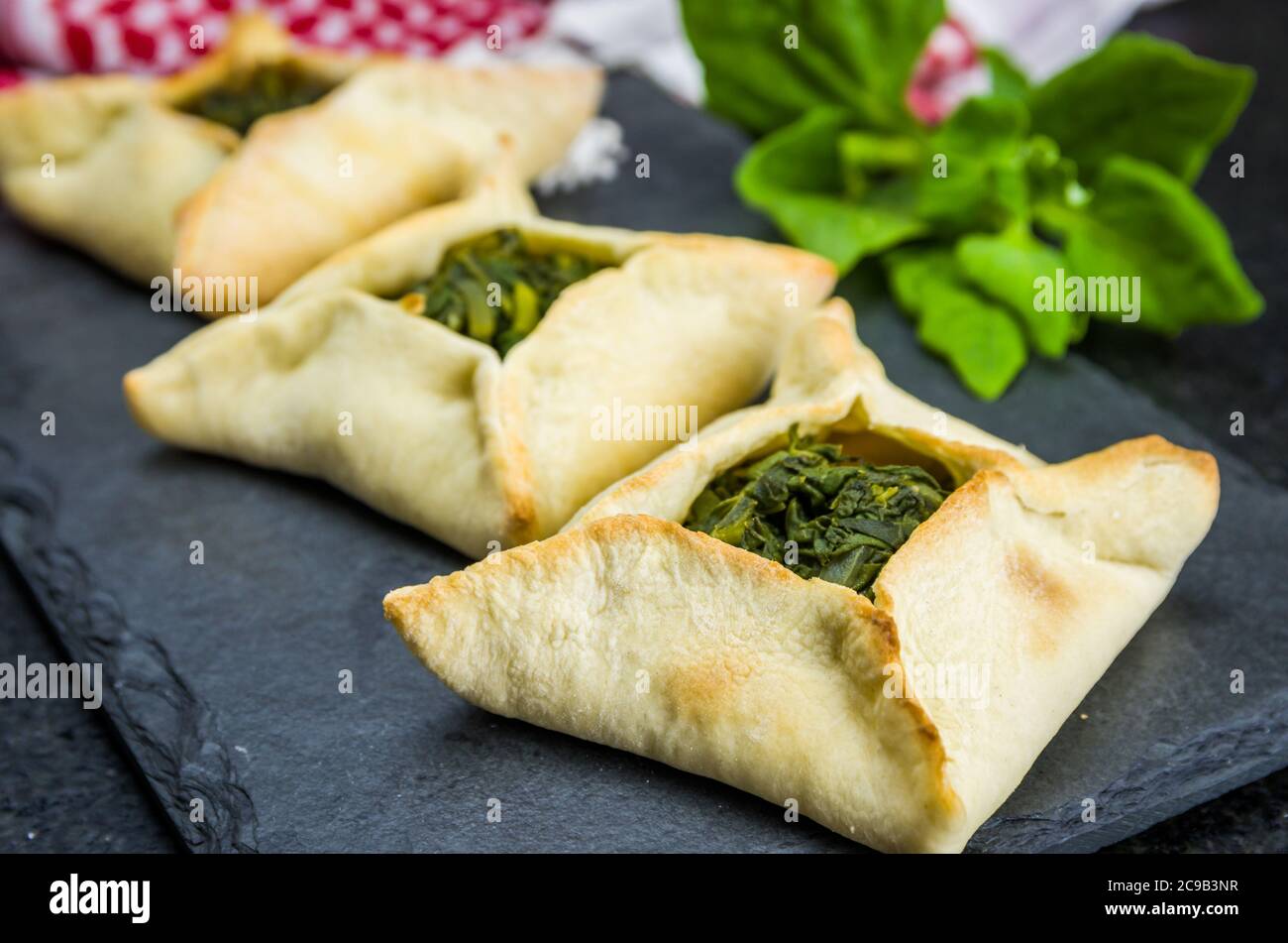 Delicious Lebanese (Arabic) food, spinach sfiha on black slate stone ...