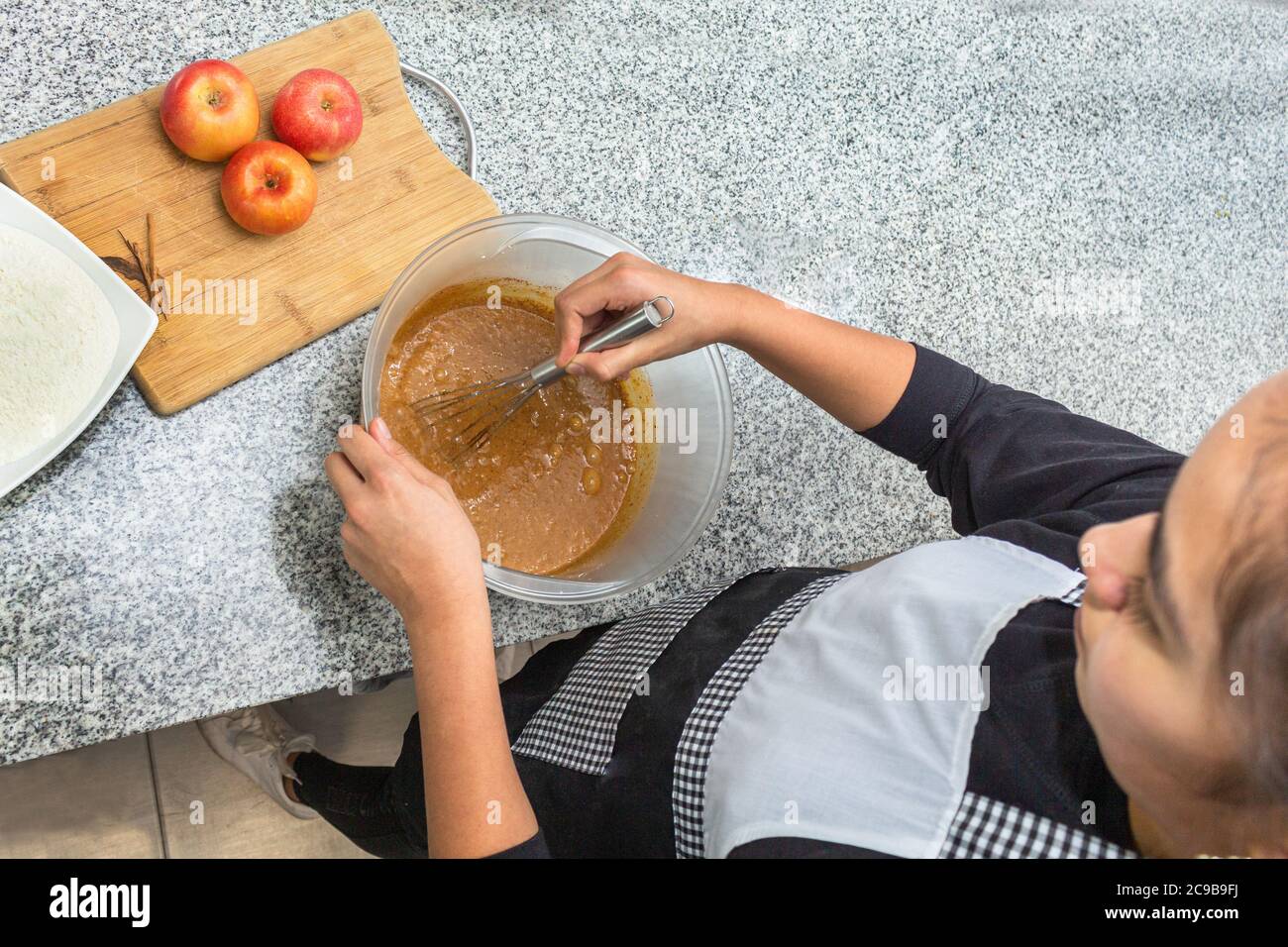 Top View of a teenage girl preparing a cake mix with a group of apples ...