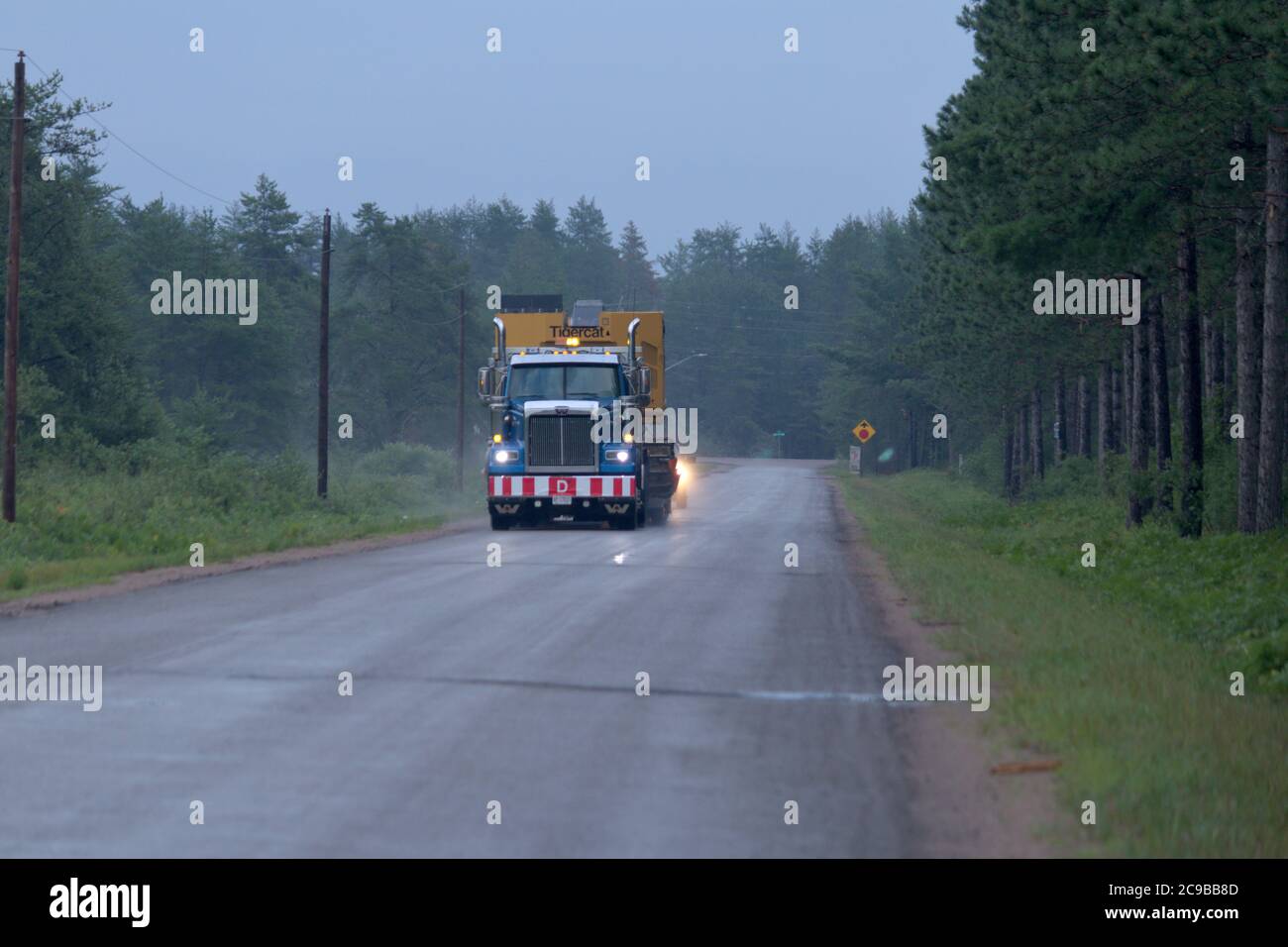 transport carrying a backhoe driving down the road Stock Photo - Alamy
