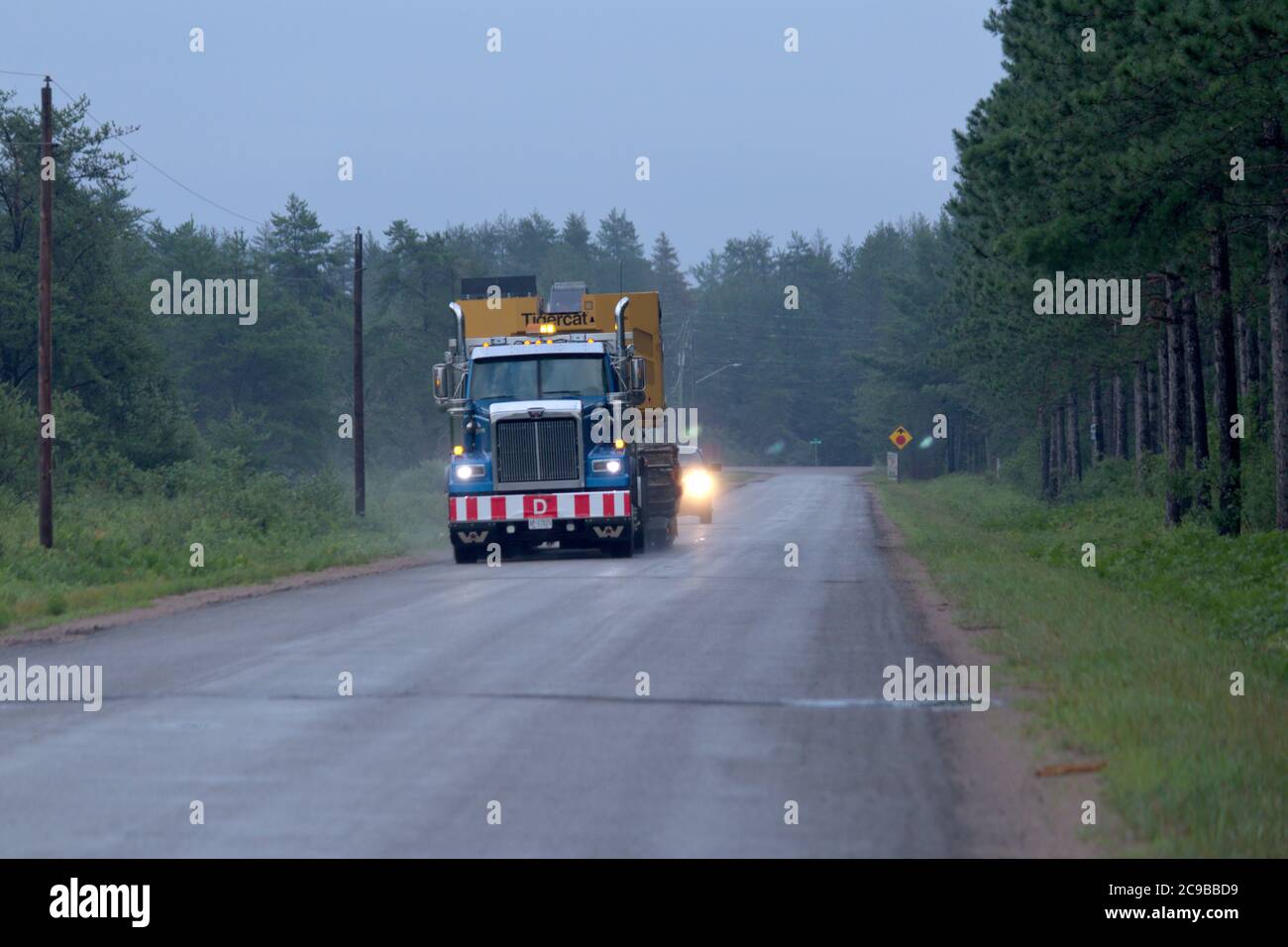 transport carrying a backhoe driving down the road Stock Photo - Alamy