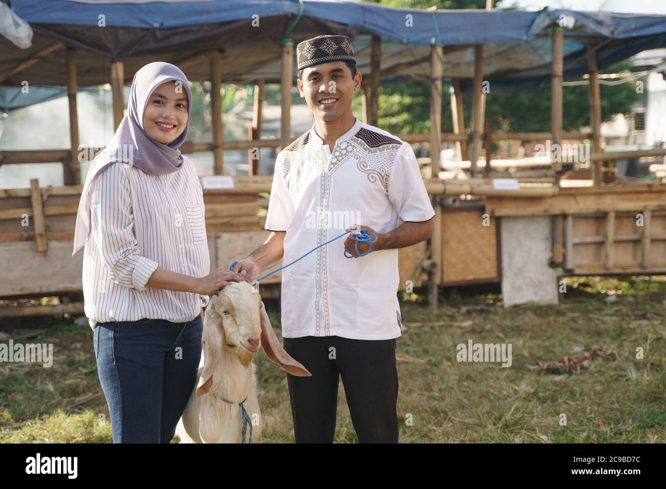 happy muslim couple buy a goat for eid adha sacrifice or qurban ...