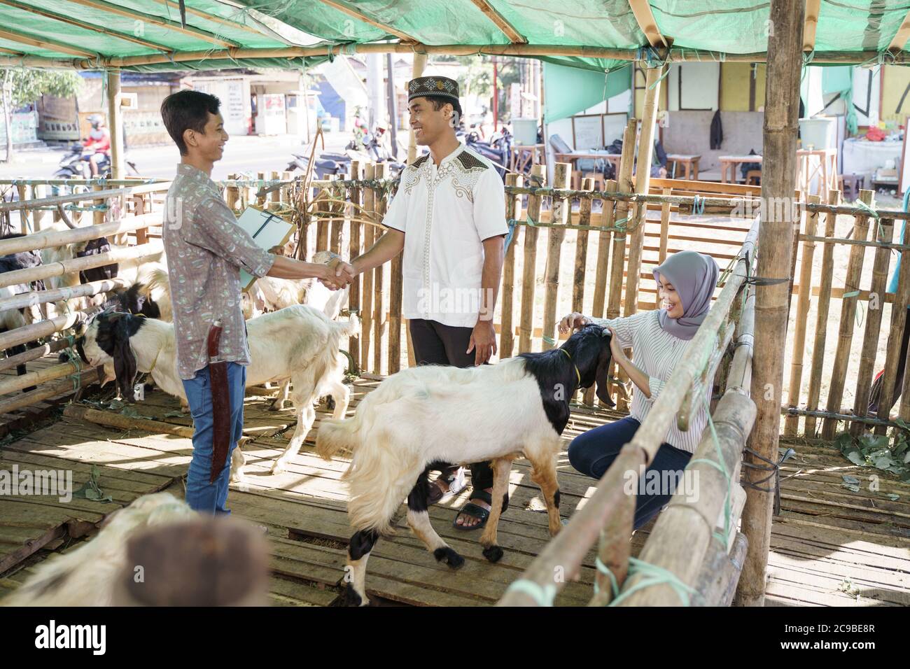 muslim people shake hand with farmer after buying a goat. idul adha ...