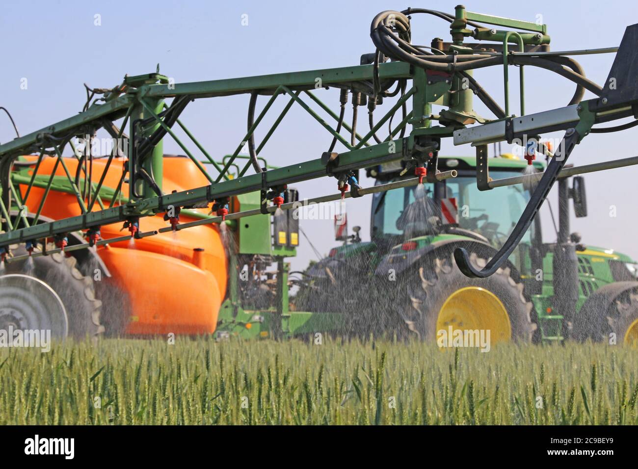 Farmer drives his tractor with crop protection sprayer over his wheat ...