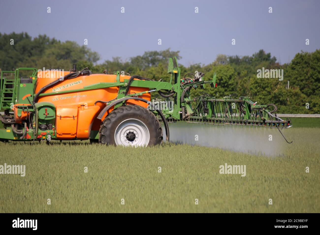 Farmer drives his tractor with crop protection sprayer over his wheat ...