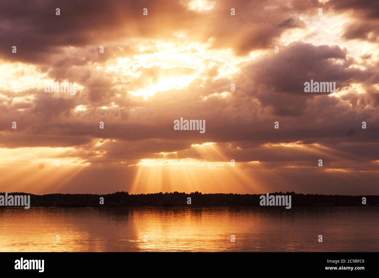 Sunset at the river. Dark horizon, orange color. Sun rays from clouds ...