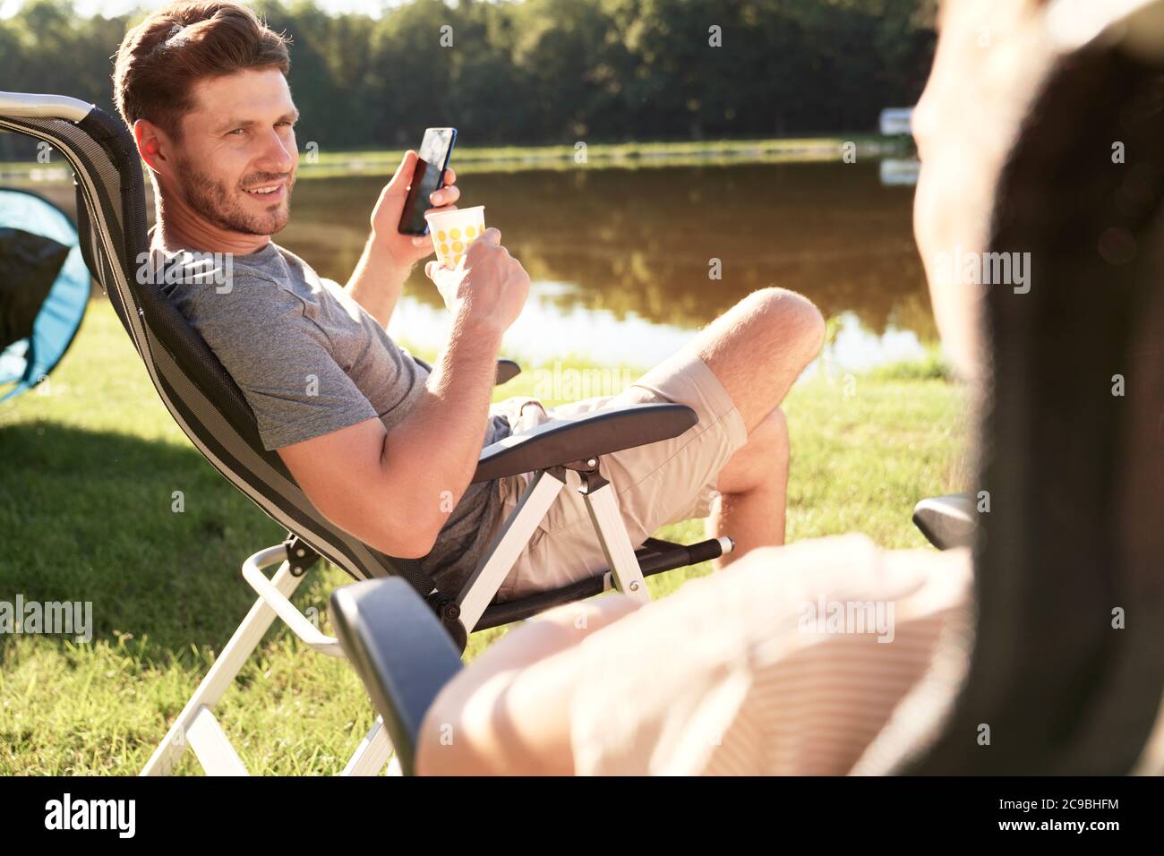 Men chilling on camping by the lake Stock Photo - Alamy