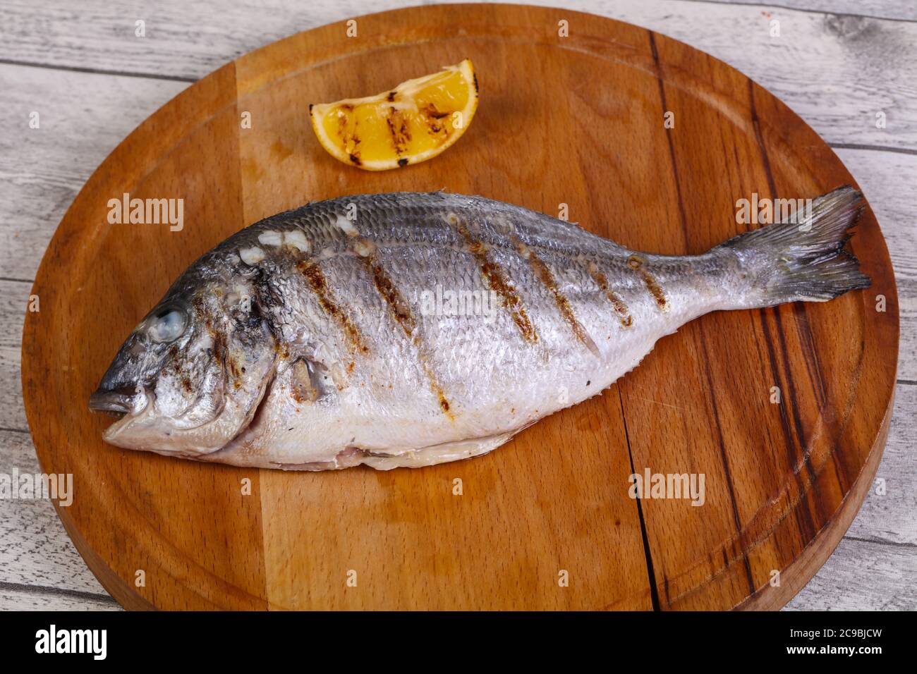 Grilled dorada with lemon over the wooden board Stock Photo - Alamy