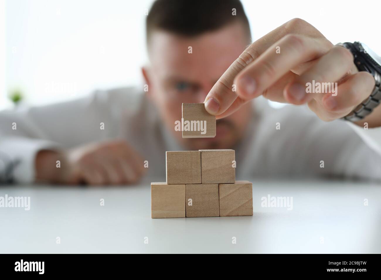 A man stacks wooden blocks on a table close-up Stock Photo - Alamy