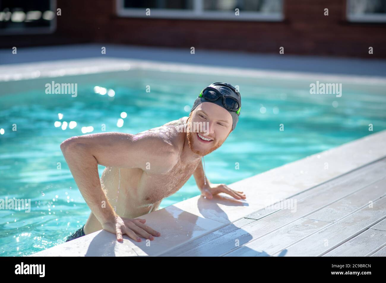 Smiling man in pool looking sideways interested Stock Photo - Alamy