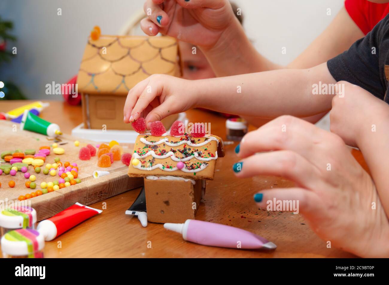 Family of three decorating home baked gingerbread houses with colorful ...