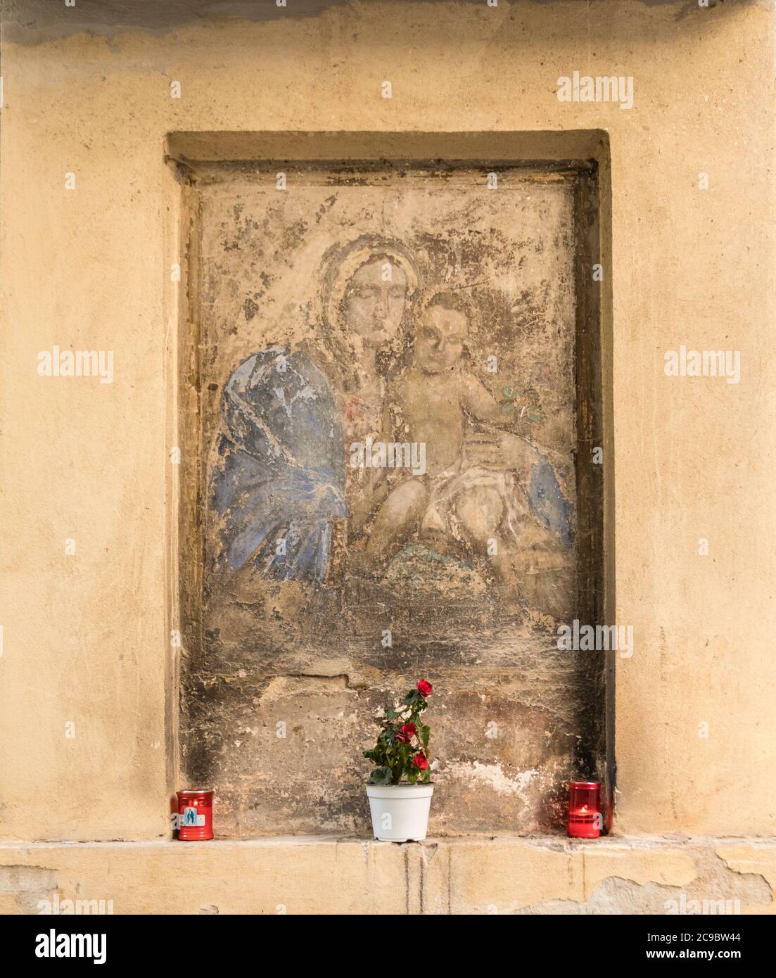 A small shrine featuring a Madonna and Child wall painting in the side ...