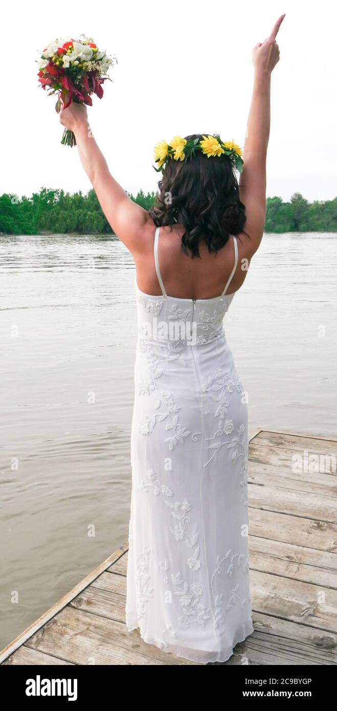 The bride from behind next to the river with both hands raise up with a ...