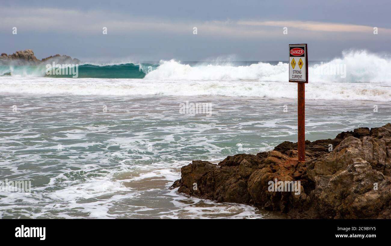 A warning sign with a big wave breaking selectively blurred on the ...