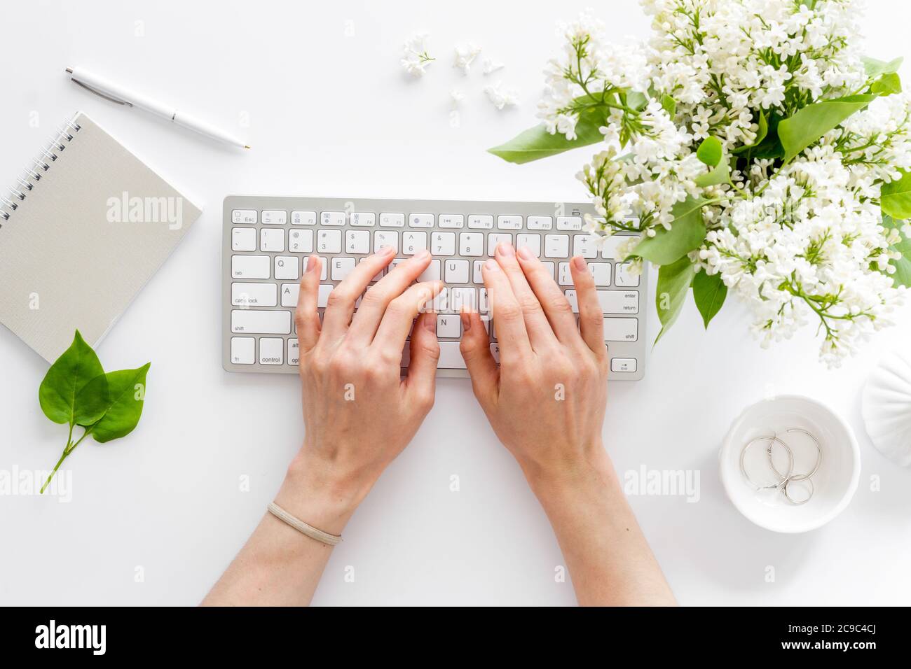 Girl typing on computer keyboard bright office space with flowers ...