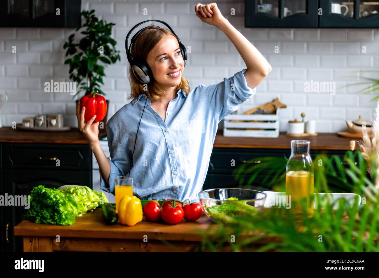 Cooking woman in the kitchen in the headphones with colorfull ...