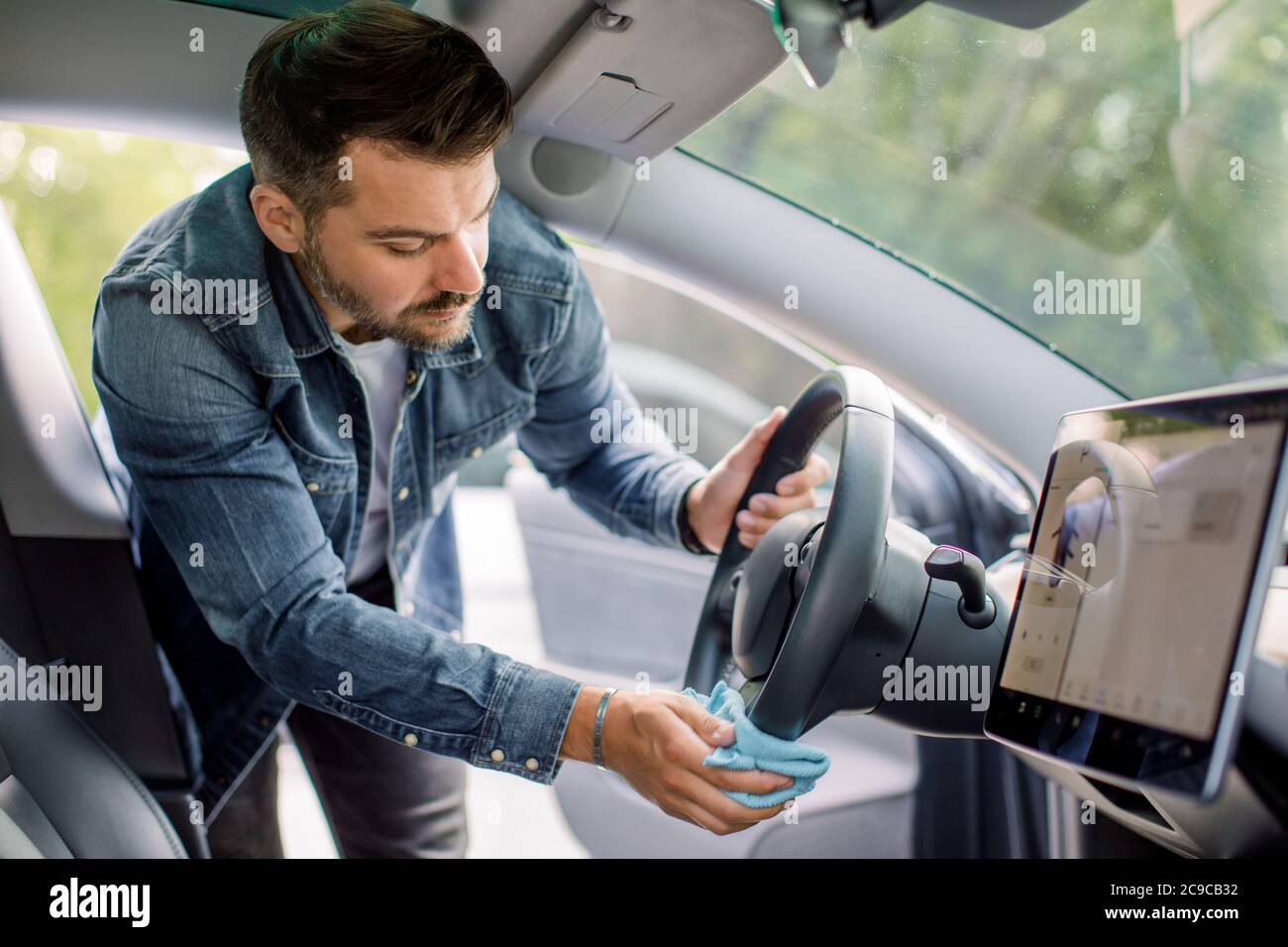 Cleaning of car interior, car detailing concept. Young Caucasian man in ...