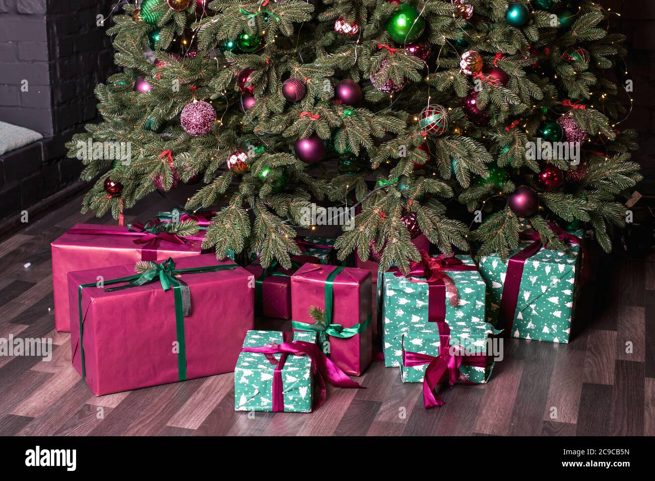 Christmas tree and pink and green gifts with ribbons underneath. New ...