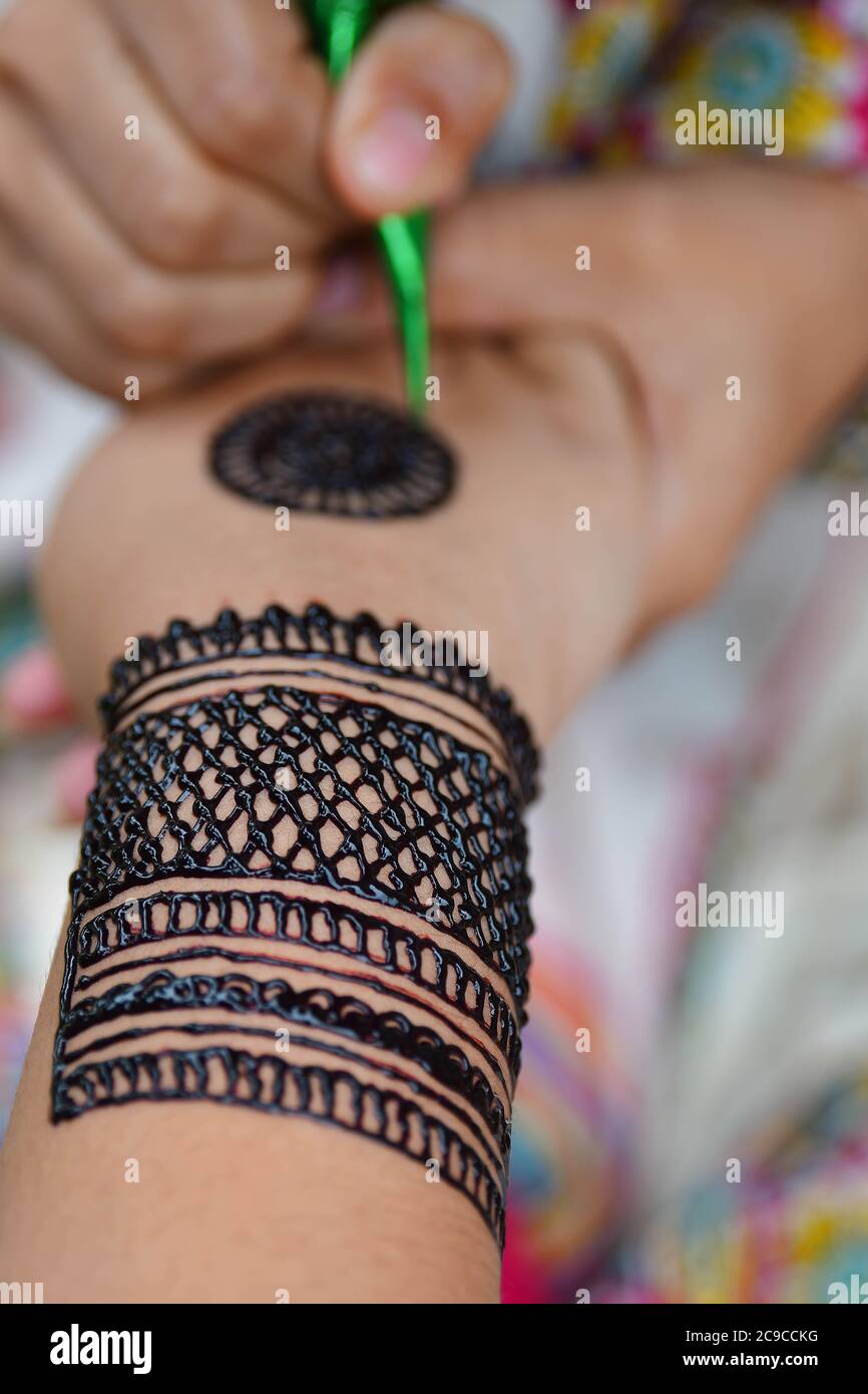 A Muslim girl gets her hands painted with traditional henna designs ...