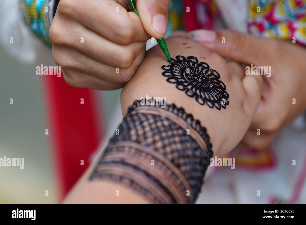 A Muslim girl gets her hands painted with traditional henna designs ...