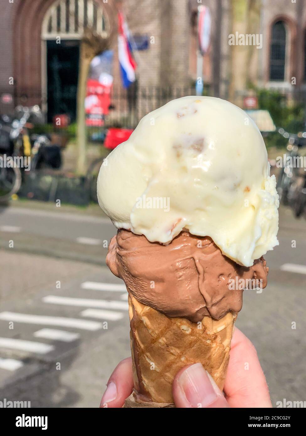 female hand holding ice cream cone at street in Europe Stock Photo - Alamy