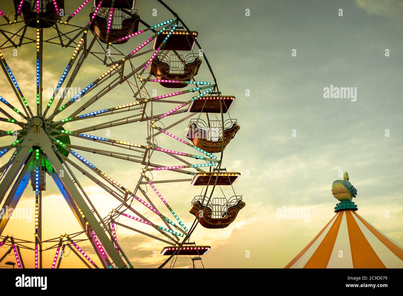 Colorful ferris wheel at sunset, illuminated by neon lights with a ...